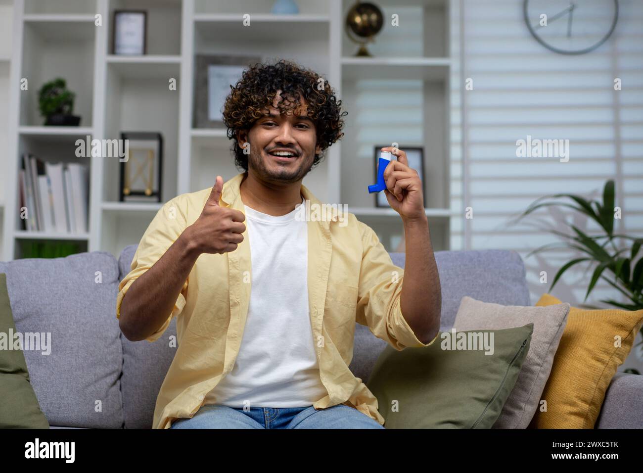 Adult male in a casual outfit using an asthma inhaler while giving a ...