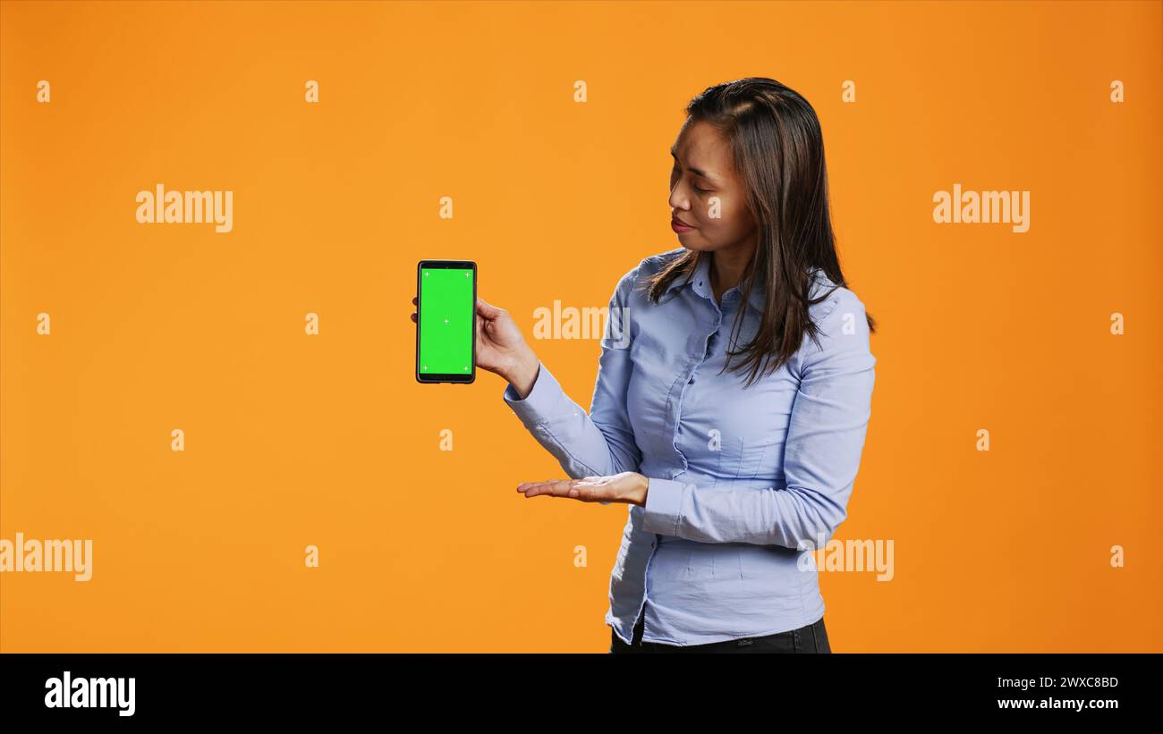 Female model presents greenscreen on phone layout, standing against ...