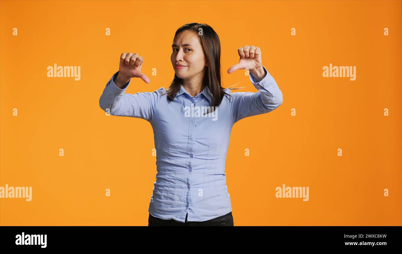 Asian person giving thumbs down in front of studio camera, expressing ...
