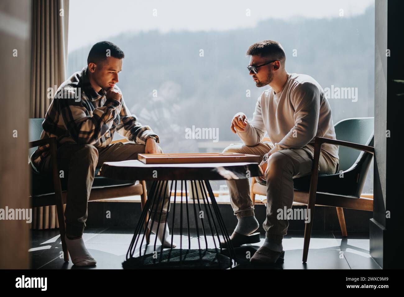 Two friends engaged in a strategic game of backgammon indoors Stock ...