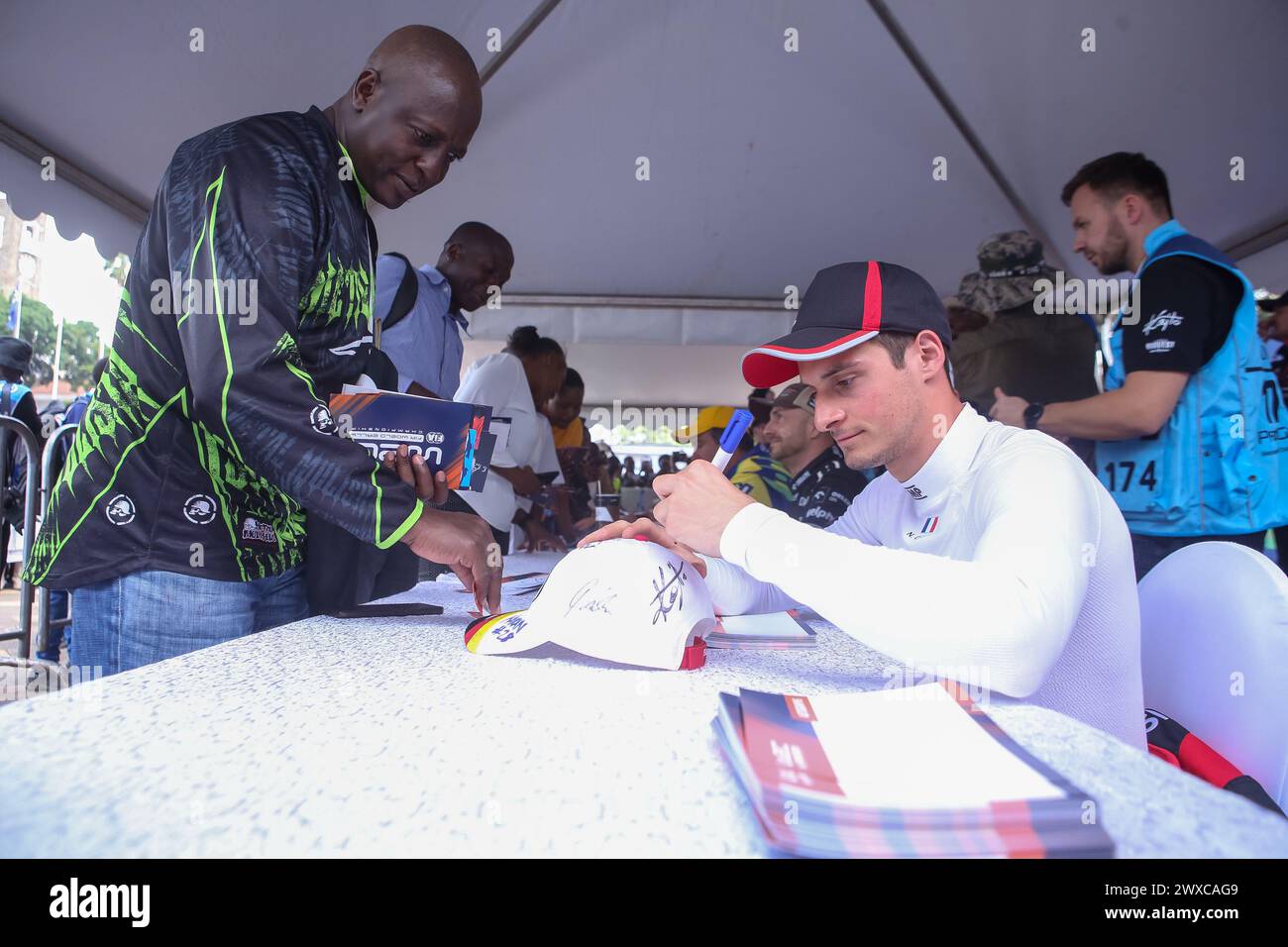 A Kenyan man gets an autograph on a cap from Nicolas Ciamin one of the rally drivers during the ...