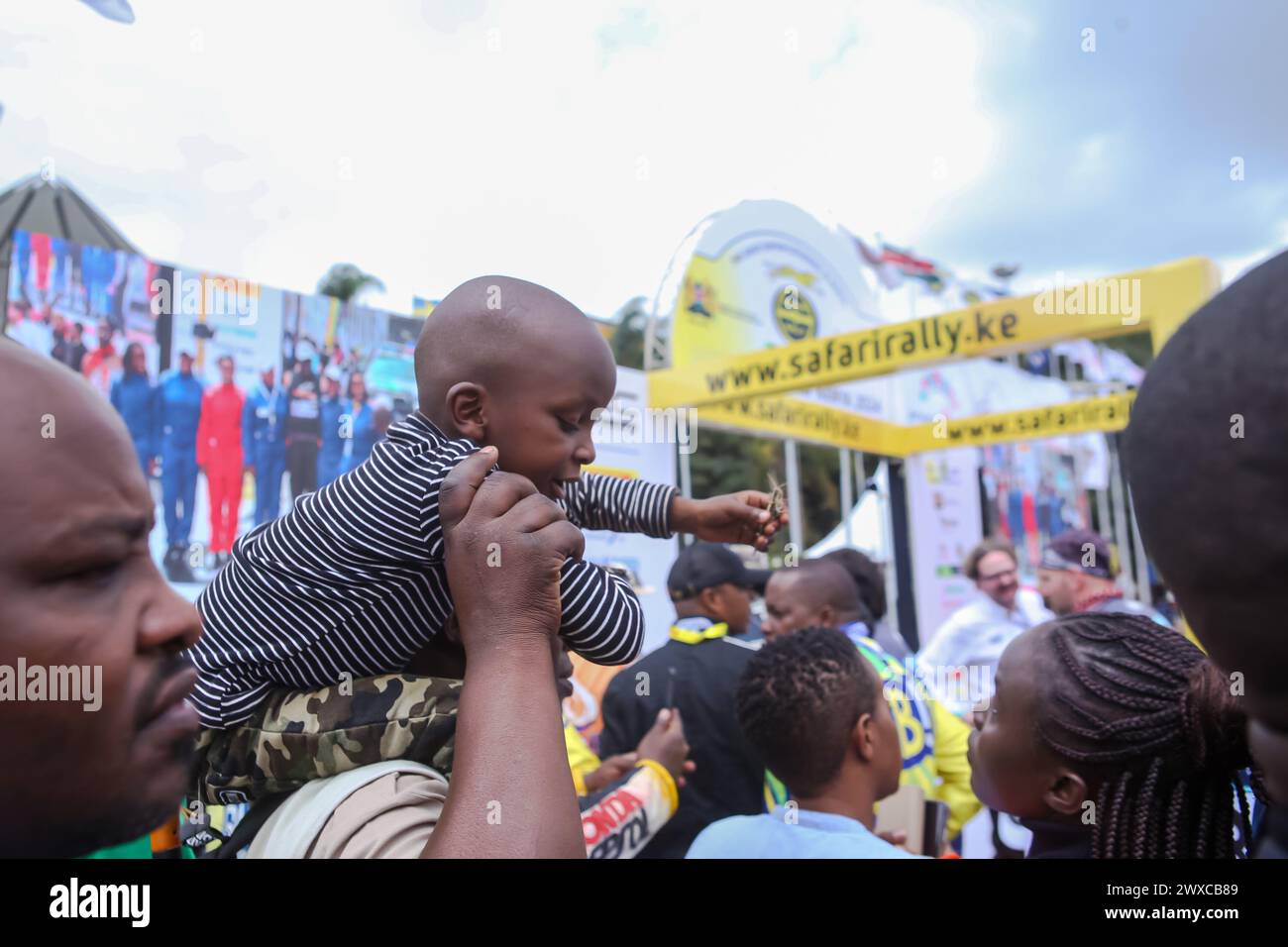 A Kenyan boy is carried by his dad during the official flagging off ...