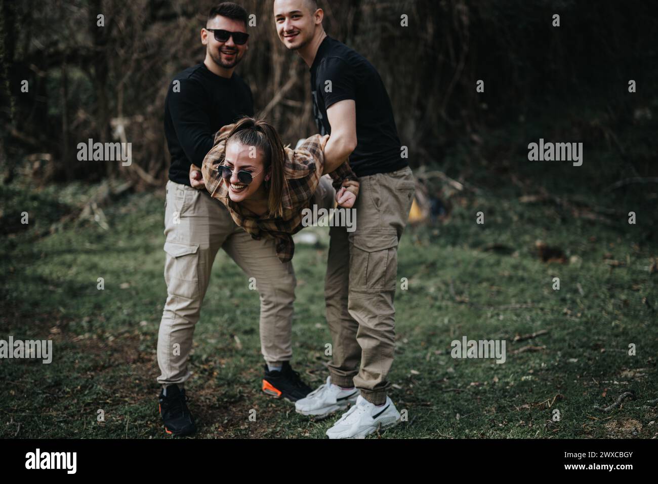 Three friends enjoying a playful moment in a forest setup Stock Photo ...