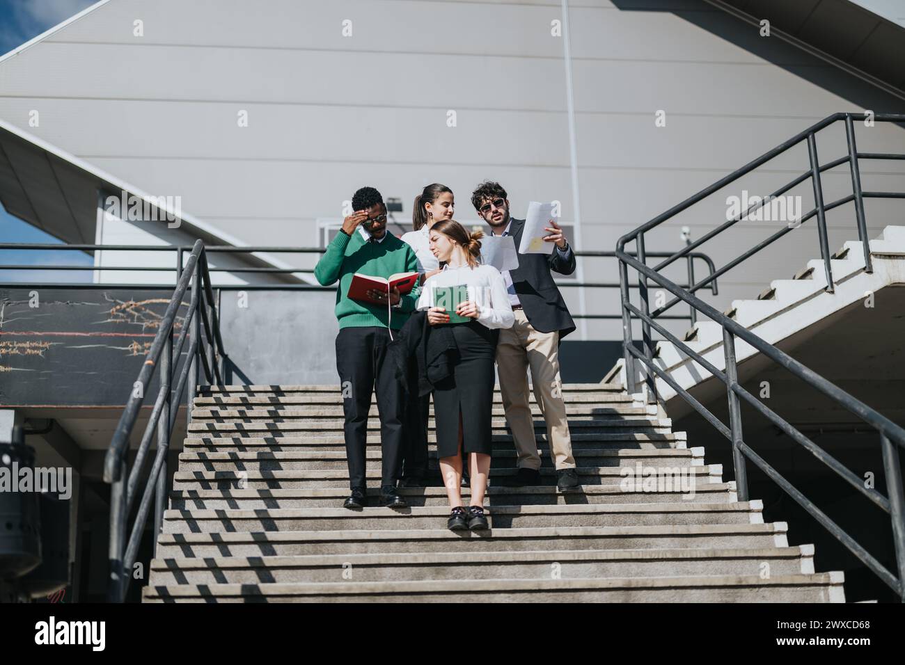 Multicultural business team strategizing on outdoor stairs discussing ...