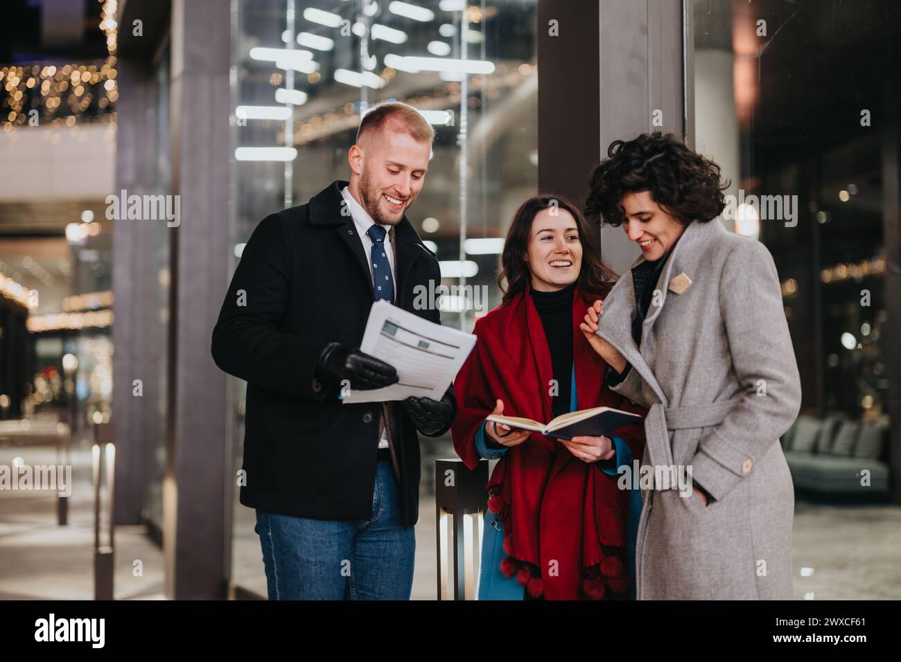Three young business colleagues sharing a light moment outside a corporate building at night ...