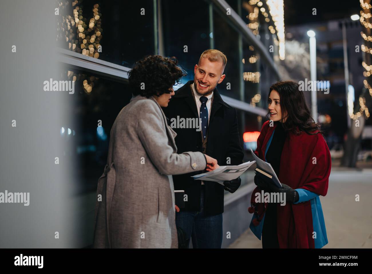 Three colleagues gather for an informal business meeting at dusk ...