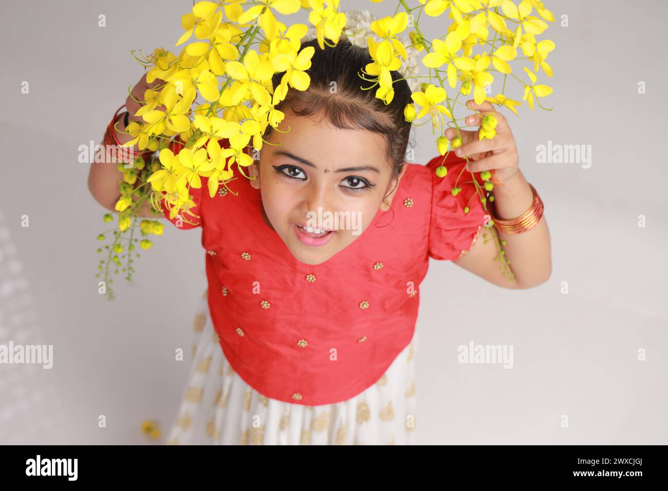 A cute small girl child wearing Kerala dress-golden colour long skirt and red blouse with golden ...