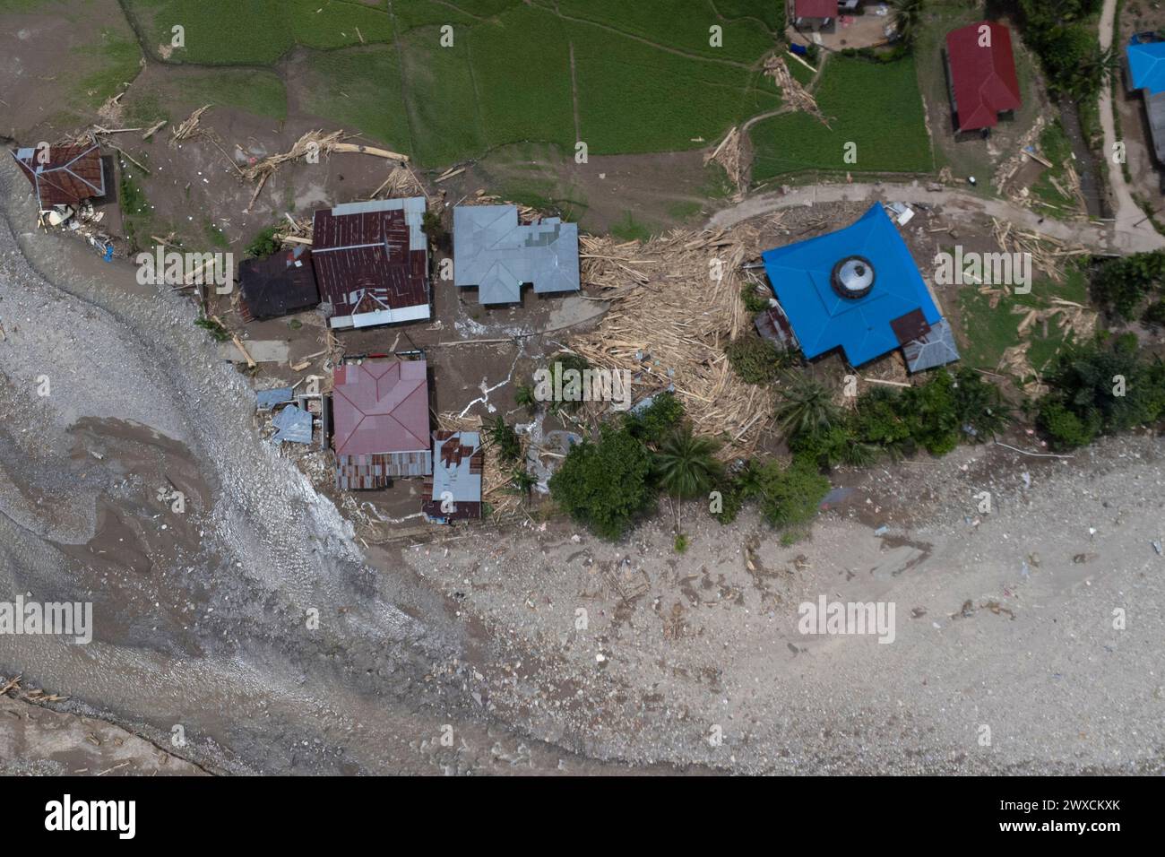 Logs that were swept into a village after a flash flood are visible in ...
