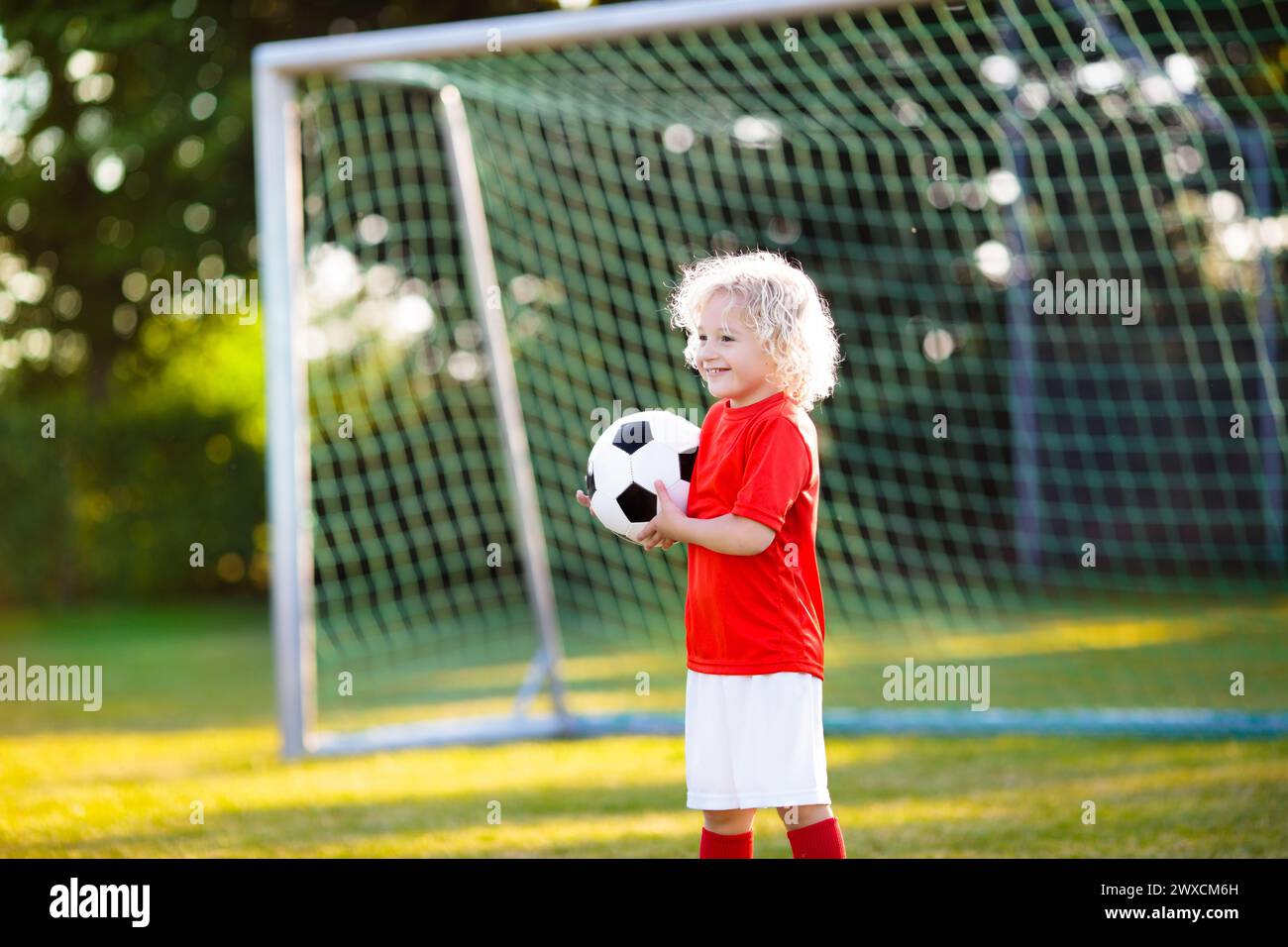 Kids play football on outdoor field. Children score a goal at soccer ...