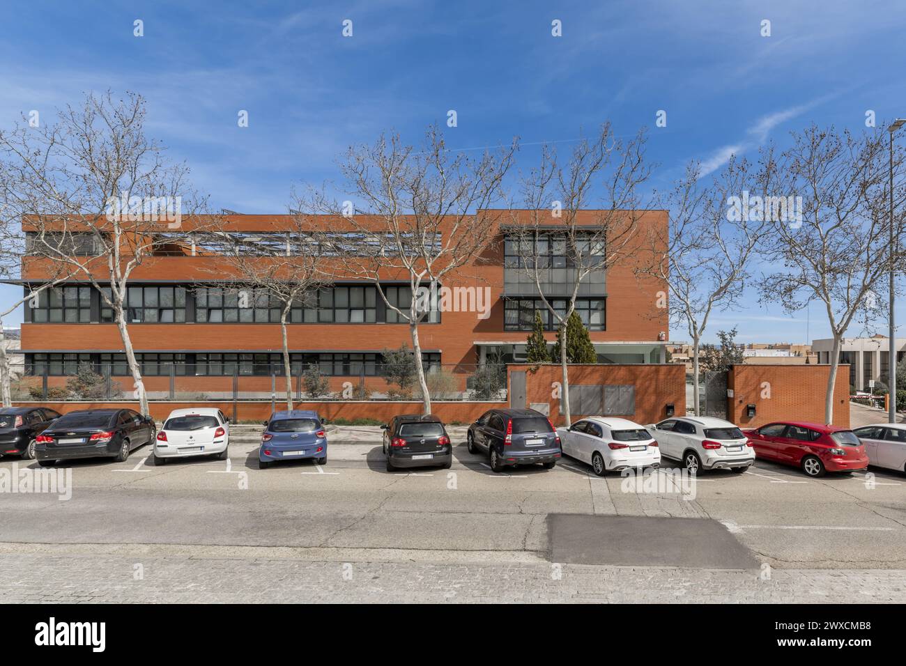Main facade of an office building with vehicles parked in parking lots ...