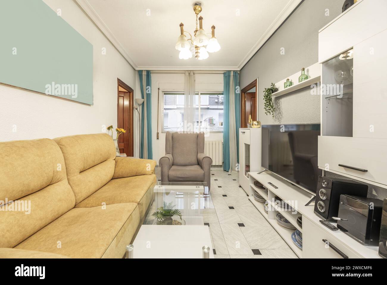 Living room with pale mustard fabric sofa in front of a white bookcase ...