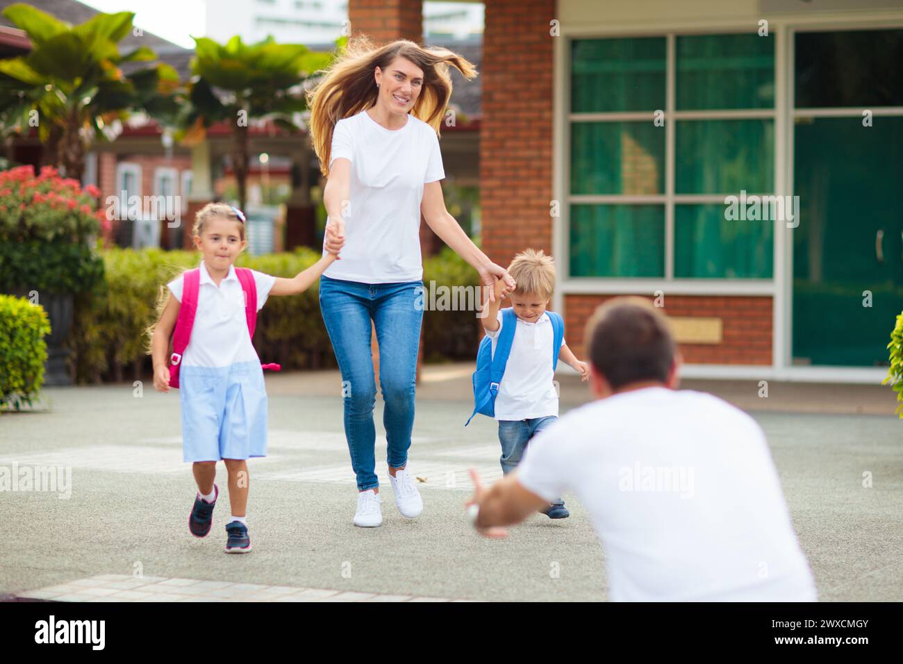 Mother and kids after school. Young mom picking up children after ...