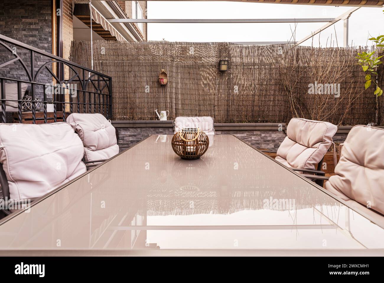 A metal and glass dining table on a plant-filled terrace with smooth ...