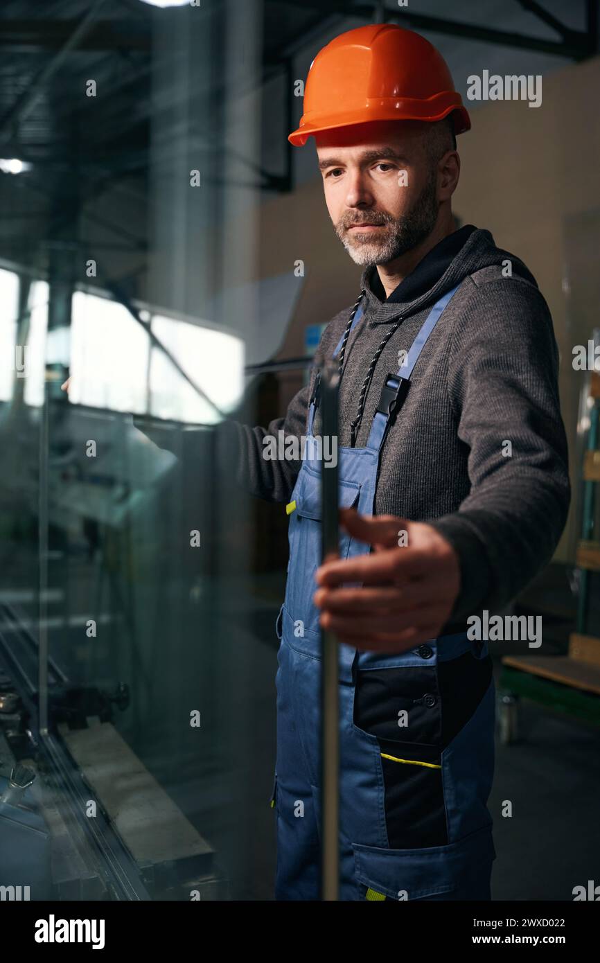 Middle-aged worker in a production workshop wearing orange safety ...