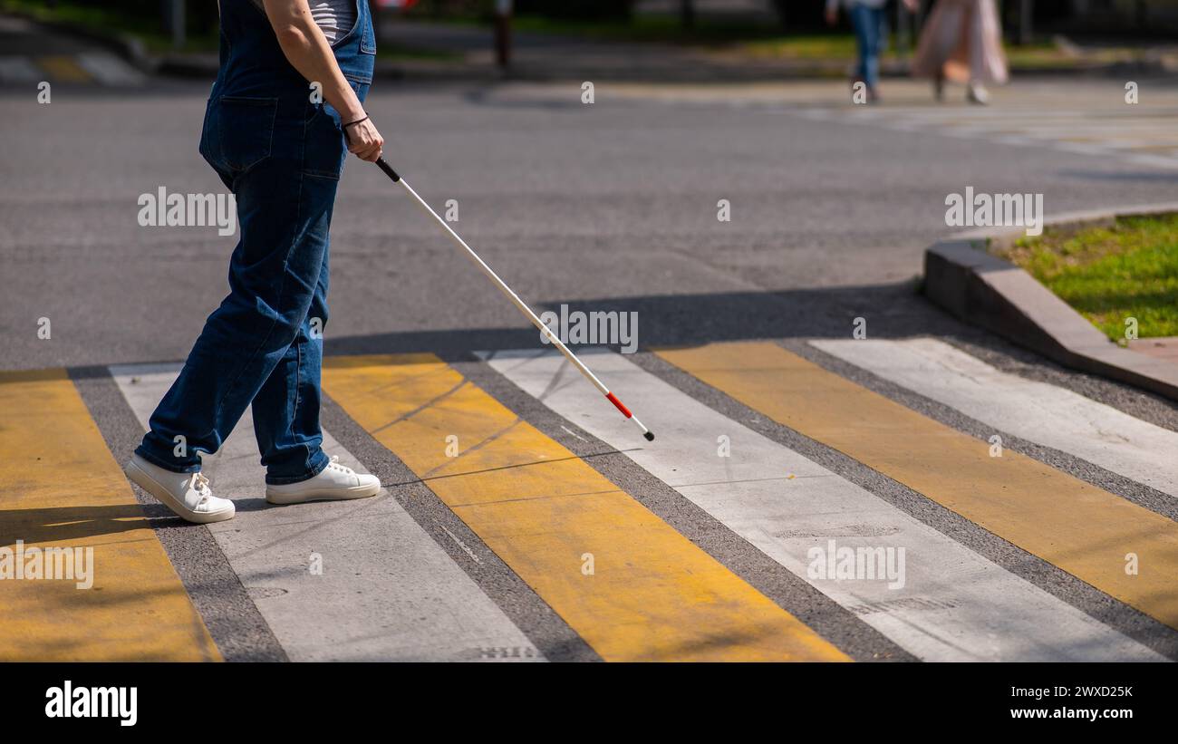 Close-up of the legs of a blind woman crossing the road at a crosswalk ...