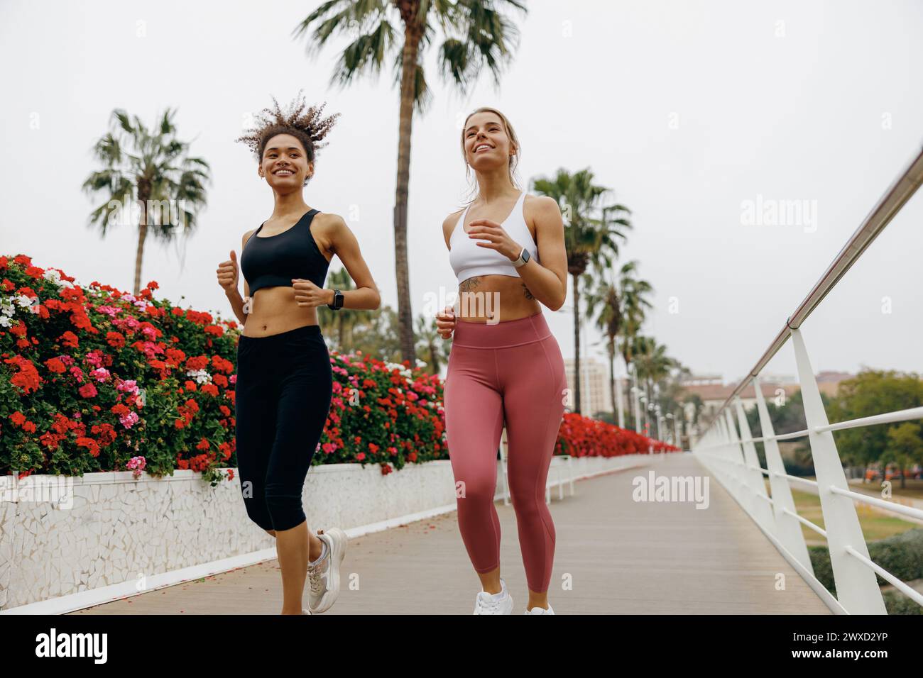 Two active women athlete running side by side along an outdoor track on ...