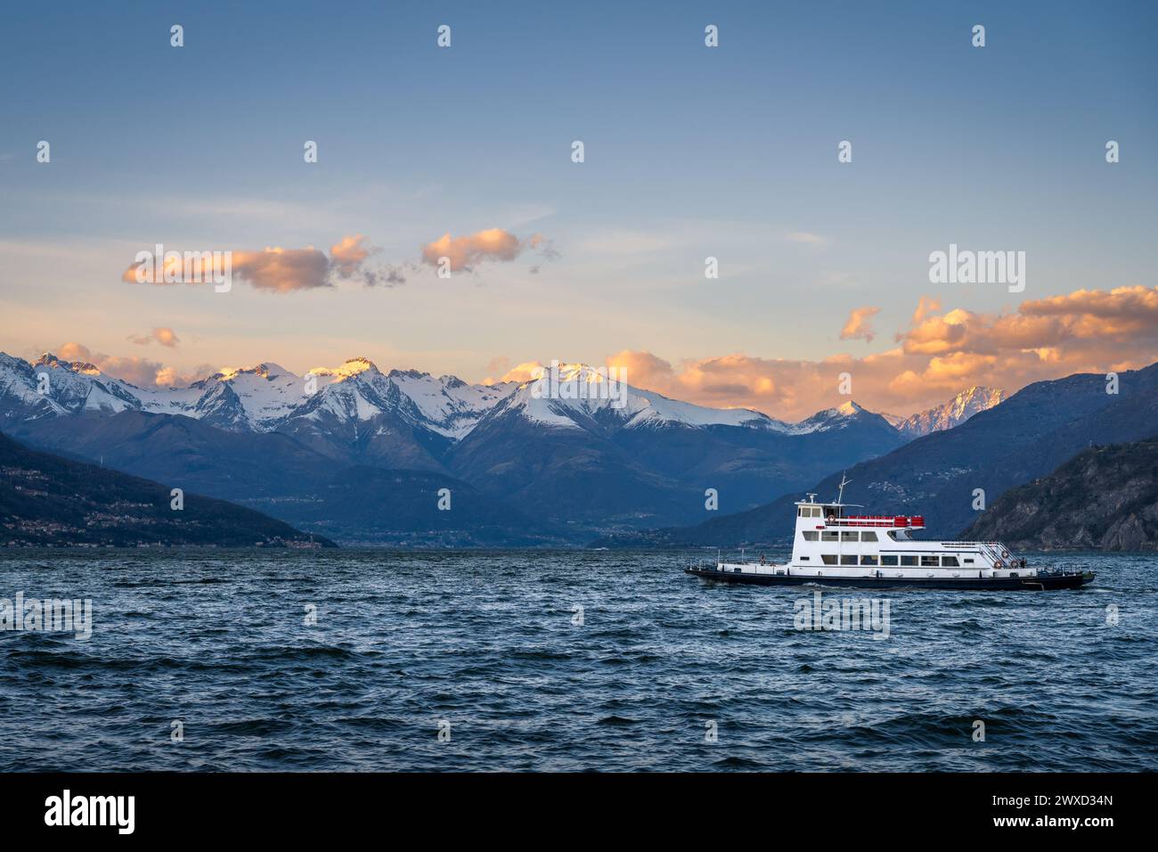 Ferry on Lake Como, Italy with snow covered mountains in the background ...