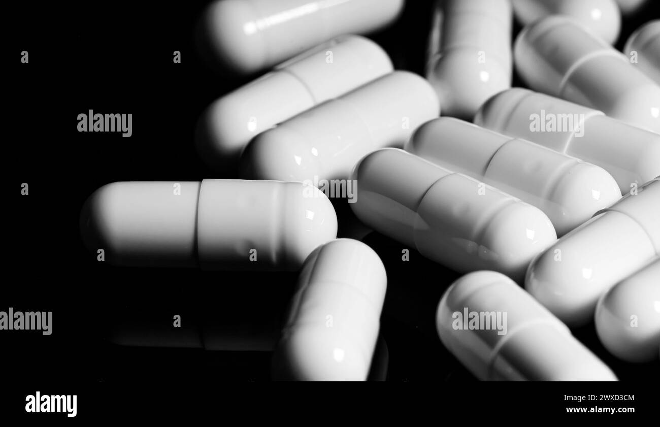 Macro Close up of white painkiller capsule on a reflective black ...