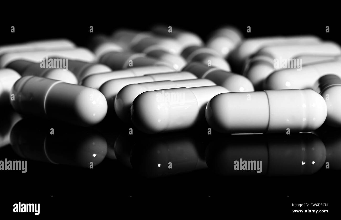 Macro Close up of white painkiller capsule on a reflective black ...