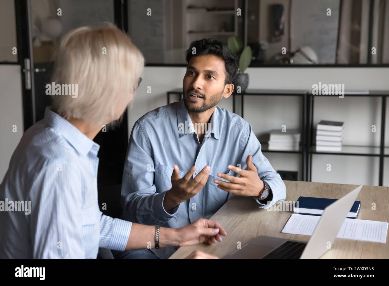 Serious younger Indian professional man talking to elder colleague ...