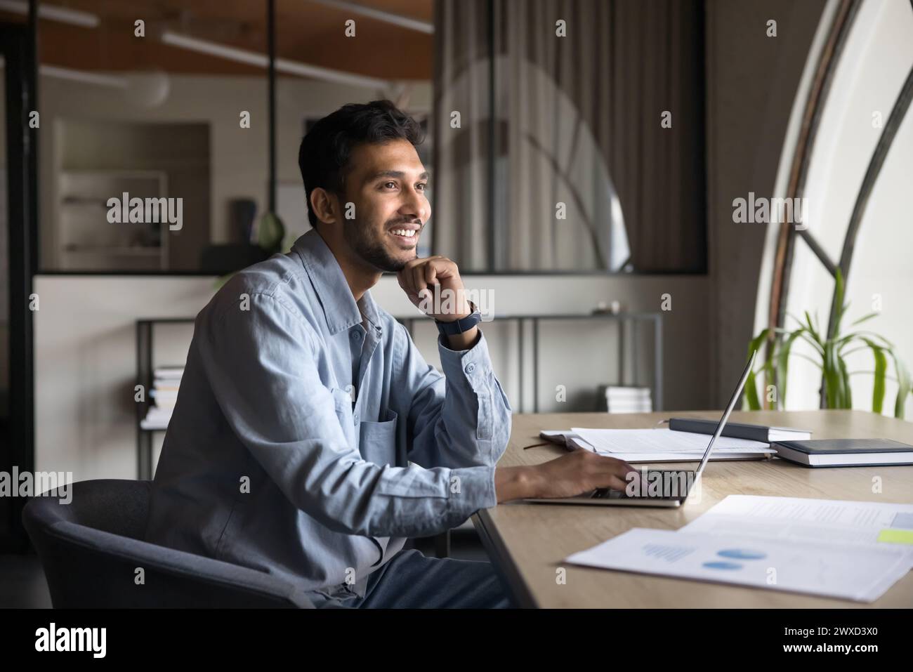 Happy dreamy young Indian professional man sitting at laptop Stock ...