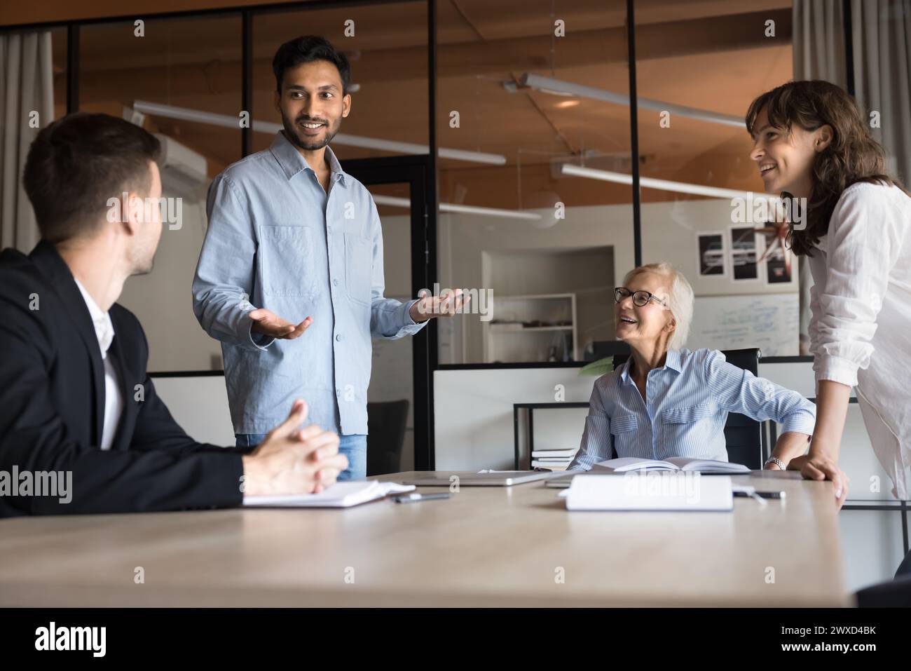 Cheerful inspired young Indian professional man presenting project plan ...