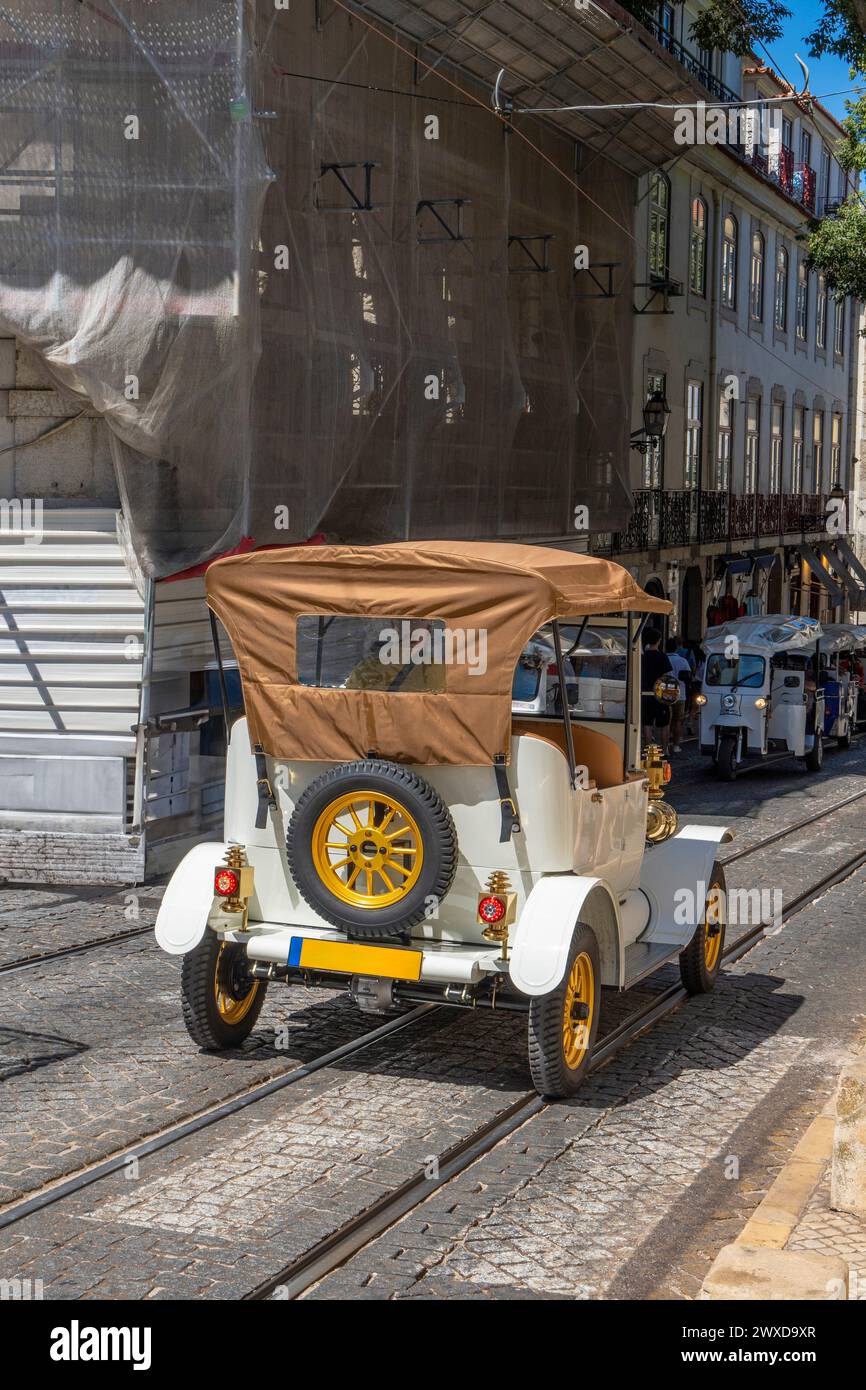 Replica of an old white electric tourist car going down a slope of a ...