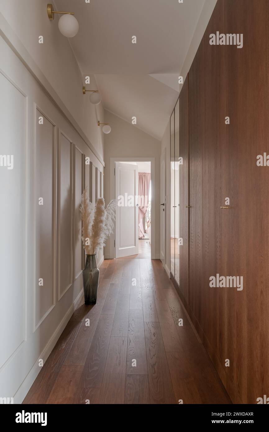 Long hallway in house features hardwood flooring, white walls Stock ...