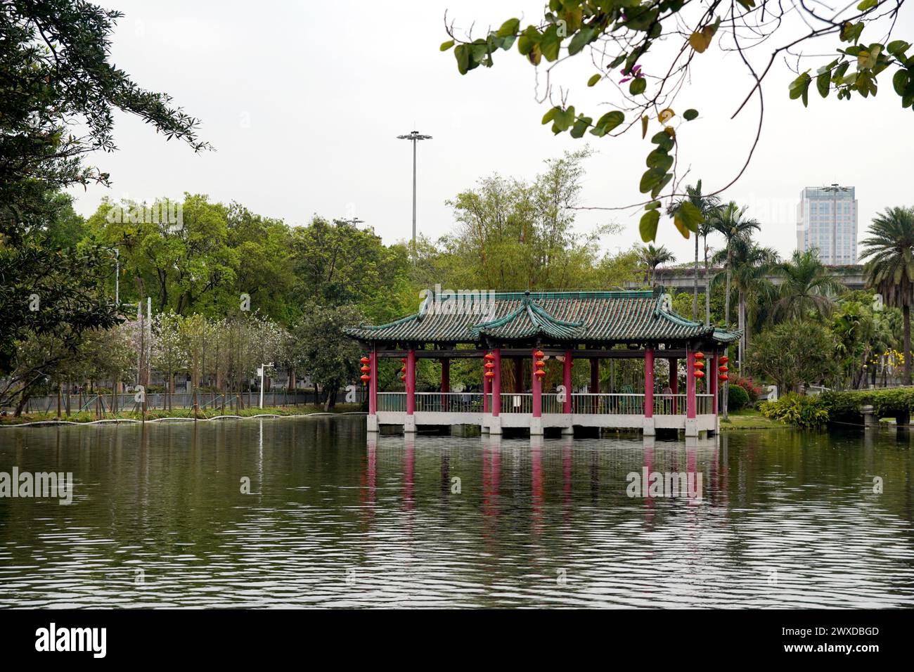 A Chinese pavilion surrounded by verdant foliage in a tranquil pond in ...