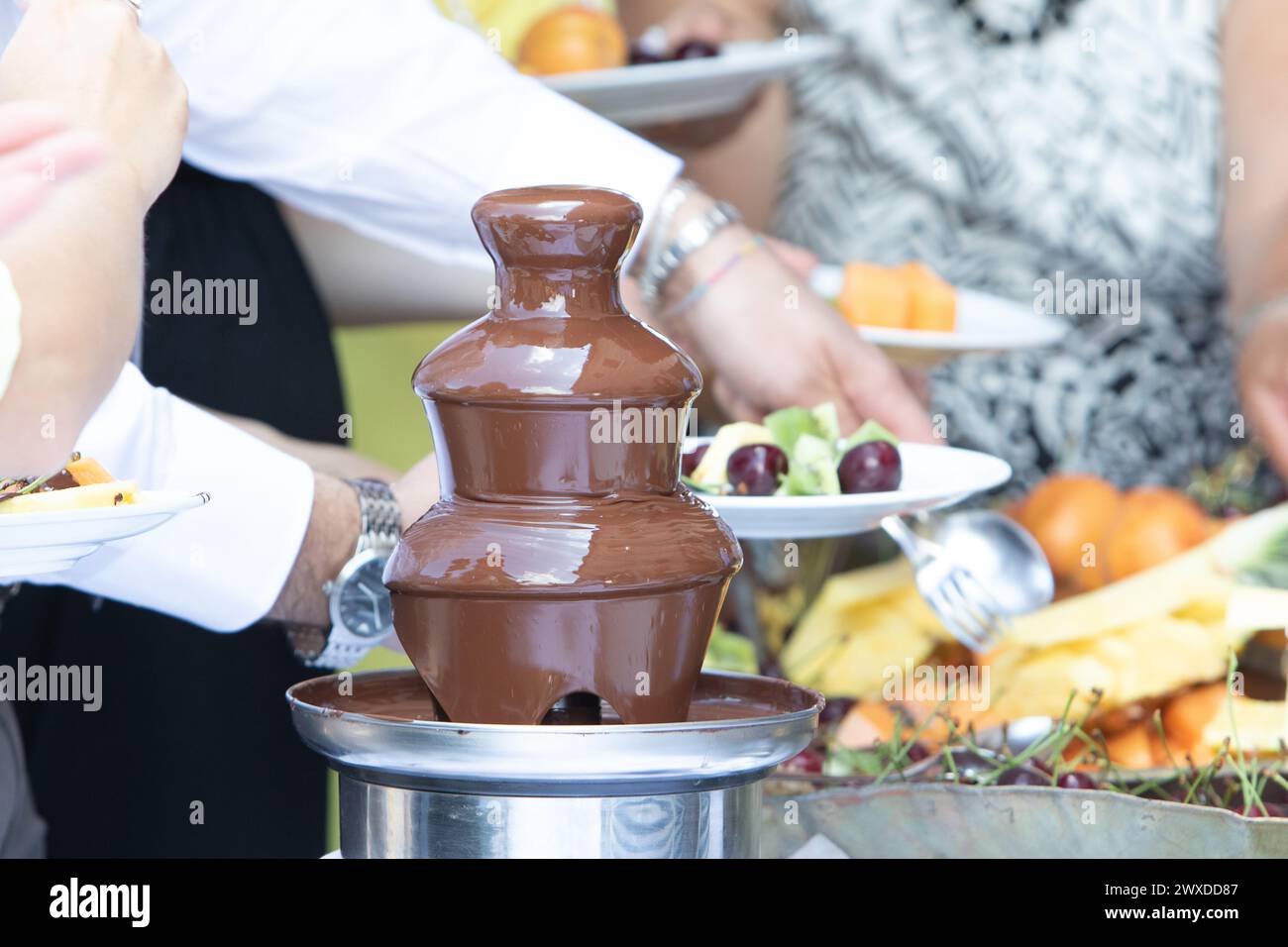 a chocolate fountain flows at a social event, where guests serve ...