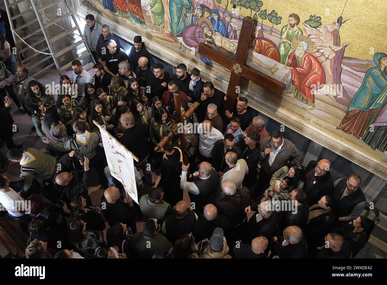 Christian Arab worshipers stand with a large wooden cross next to a ...