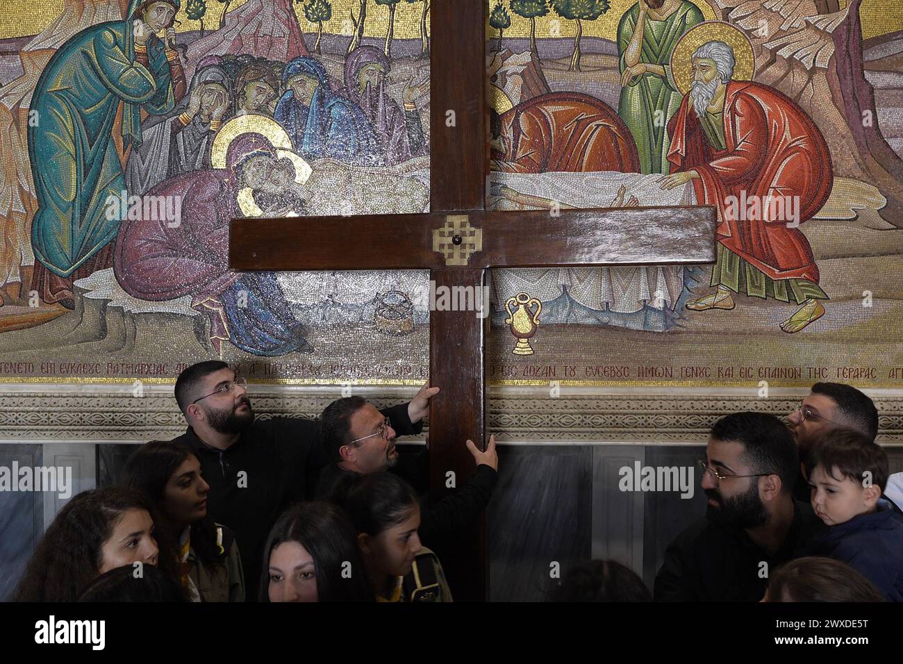 Christian Arab worshipers stand with a large wooden cross next to a ...