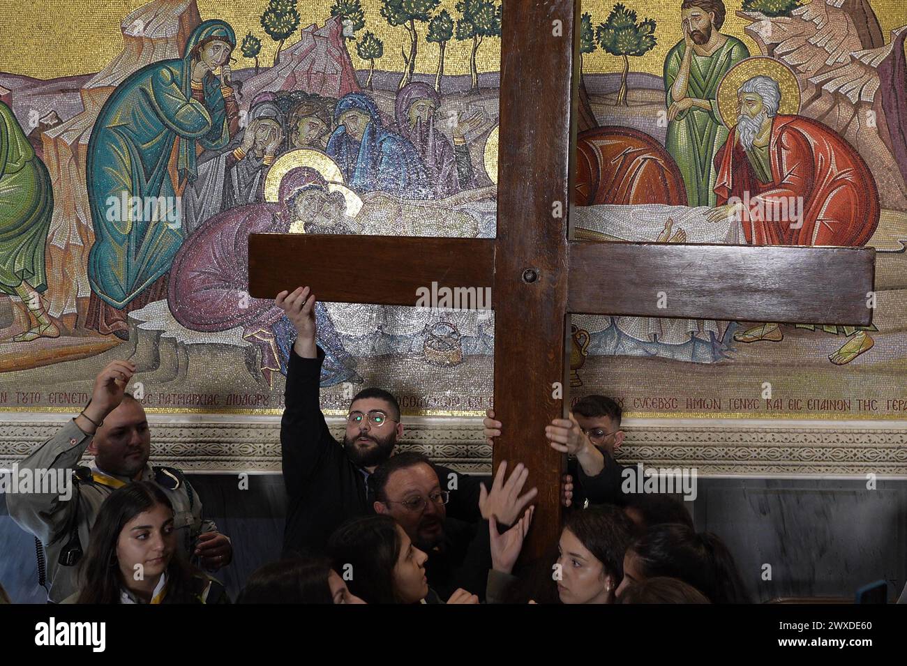 Christian Arab worshipers stand with a large wooden cross next to a ...