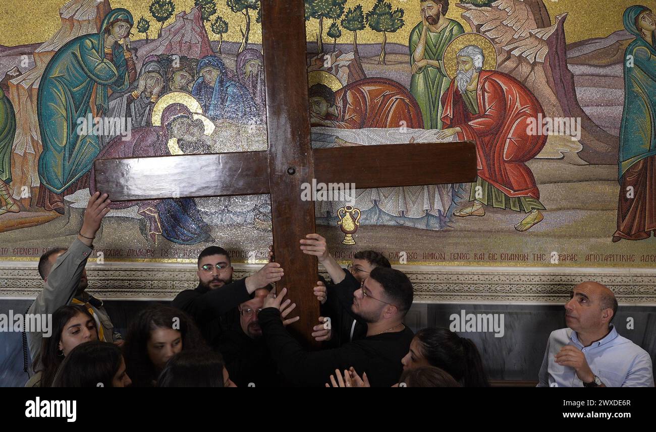 Christian Arab worshipers stand with a large wooden cross next to a ...