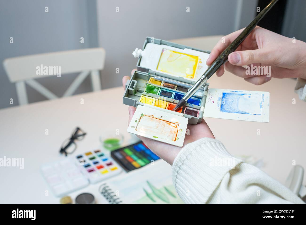 The top landscape view of a young woman shows a watercolor field kit in ...