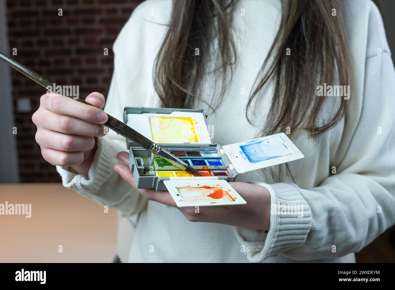 Landscape of A young woman shows a watercolor field kit in the ...