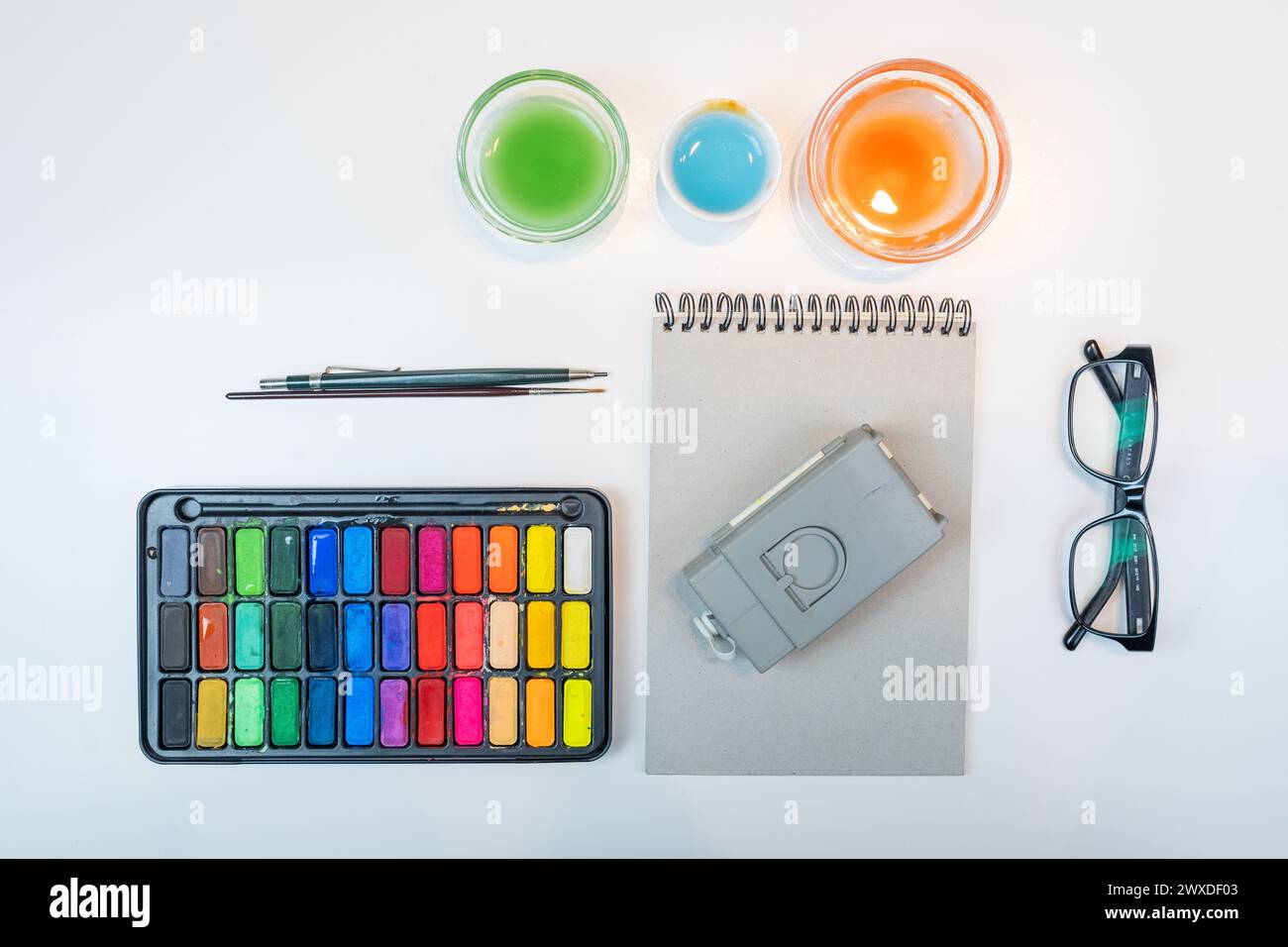 top view of arrangement of watercolor brushes and containers with water ...