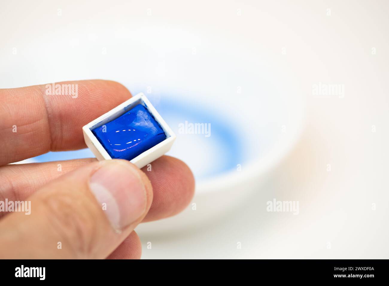 Landscape of A hand shows a mini blue watercolor cube with some more ...