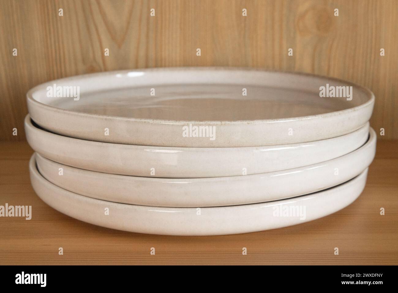 A stack of beige ceramic plates in a wooden cupboard Stock Photo - Alamy