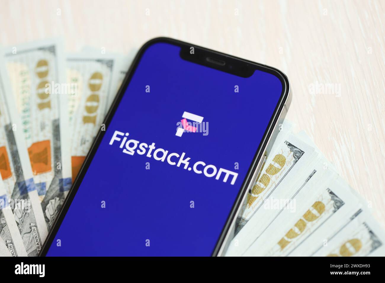 KYIV, UKRAINE - MARCH 17, 2024 Figstack logo on iPhone display screen with many hundred dollar ...