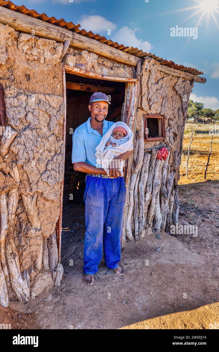 african father with one baby in the village in front of the shack, mud ...