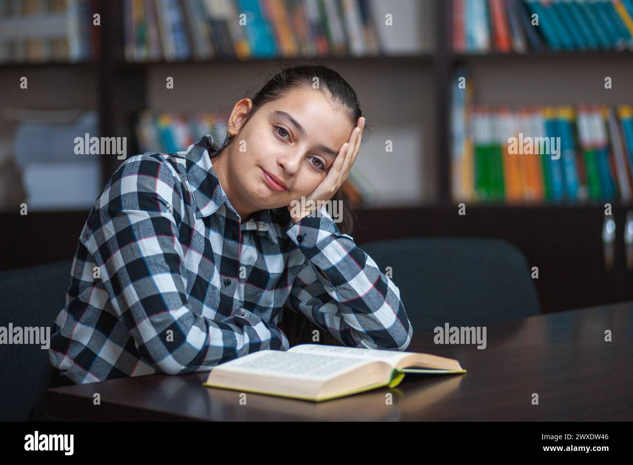beautiful schoolgirl sitting in the library and reading a book Stock ...