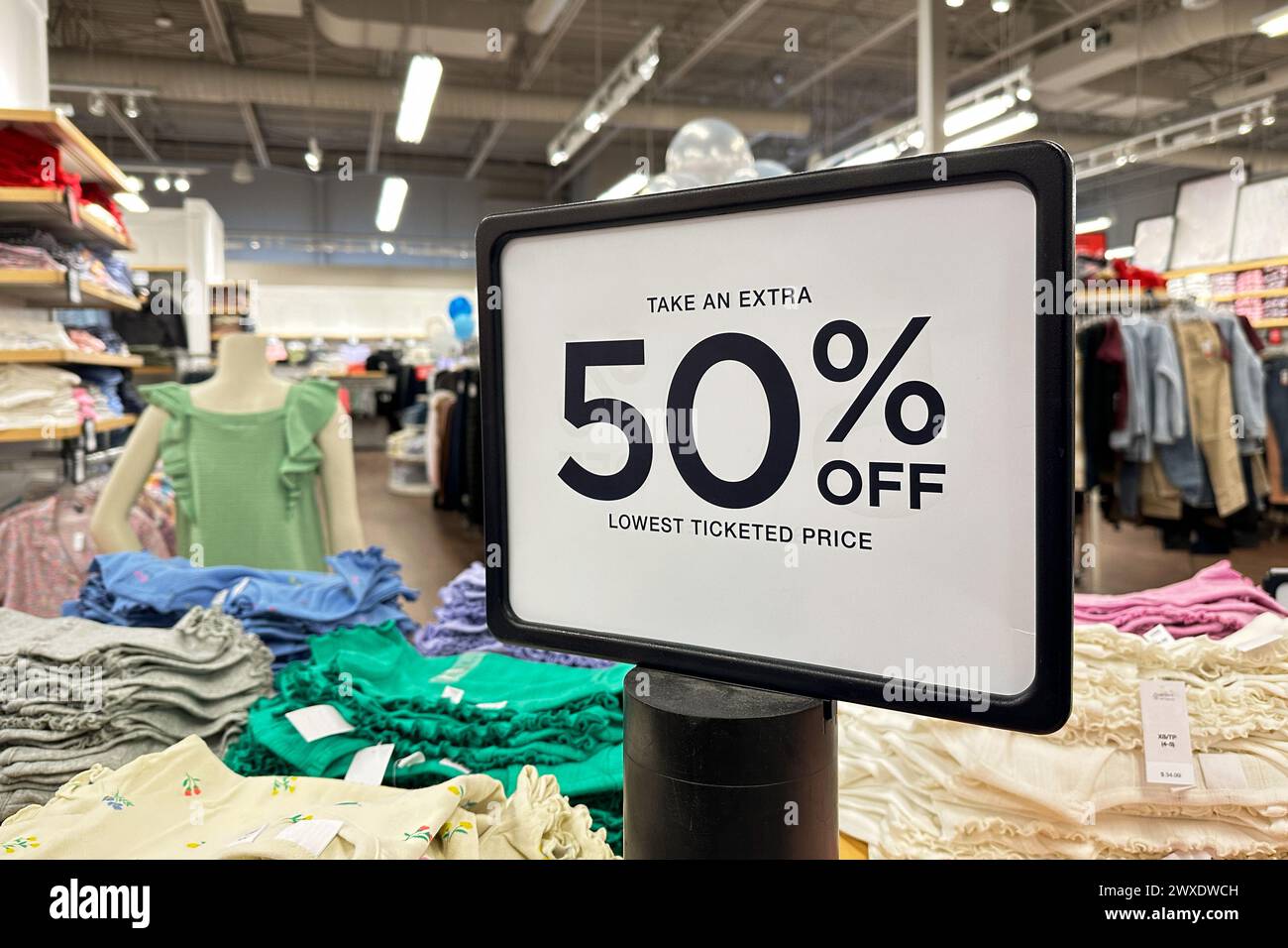 White sale word banner at clothing store entrance. Seasonal 50 percent ...