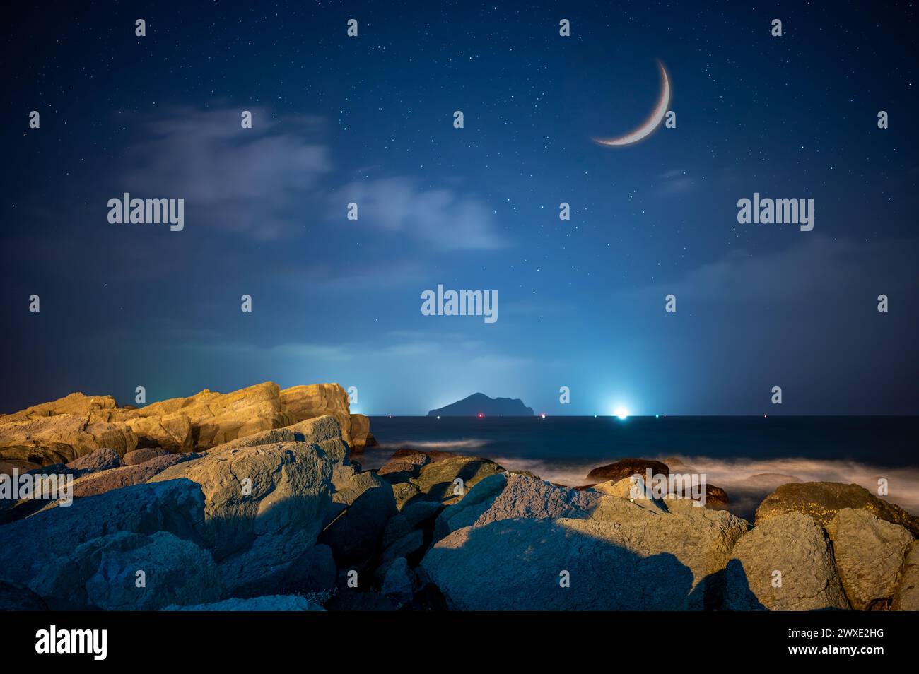 Fishing boat lights on the seaside. The charming crescent moon hangs in ...