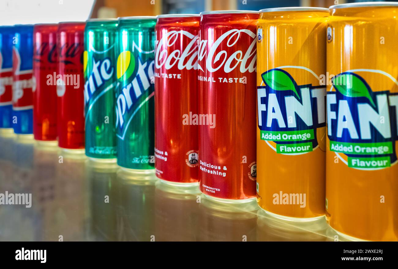 Coca-Cola Fanta Sprite products lemonade soft drinks in cans in a row on the shelf of the shop ...