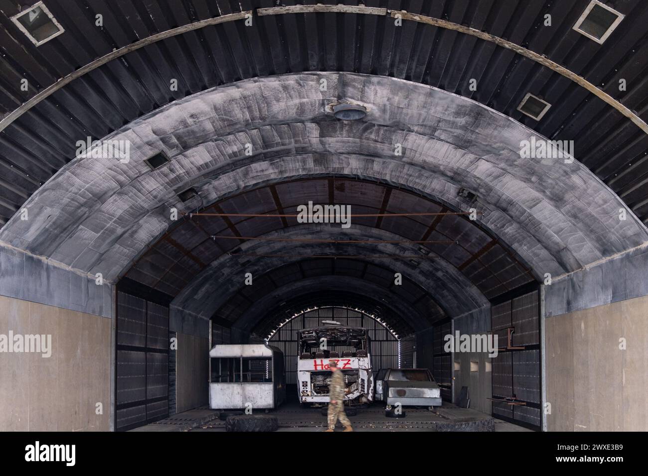 A large, empty building with a red sign on the wall. A man is walking ...