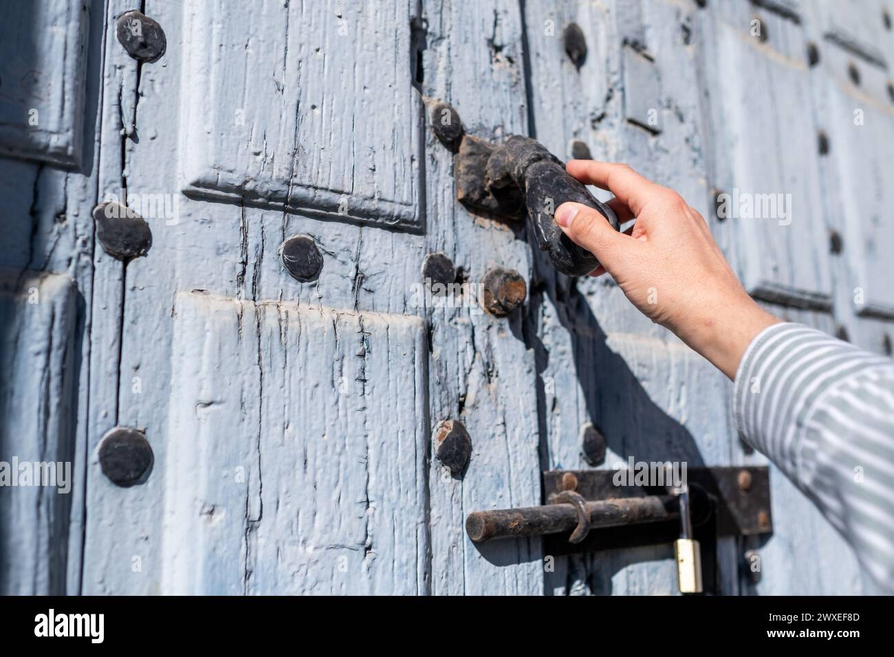 Closeup view of the hand of an unrecognizable man knocking on the wooden old door, male visitor ...
