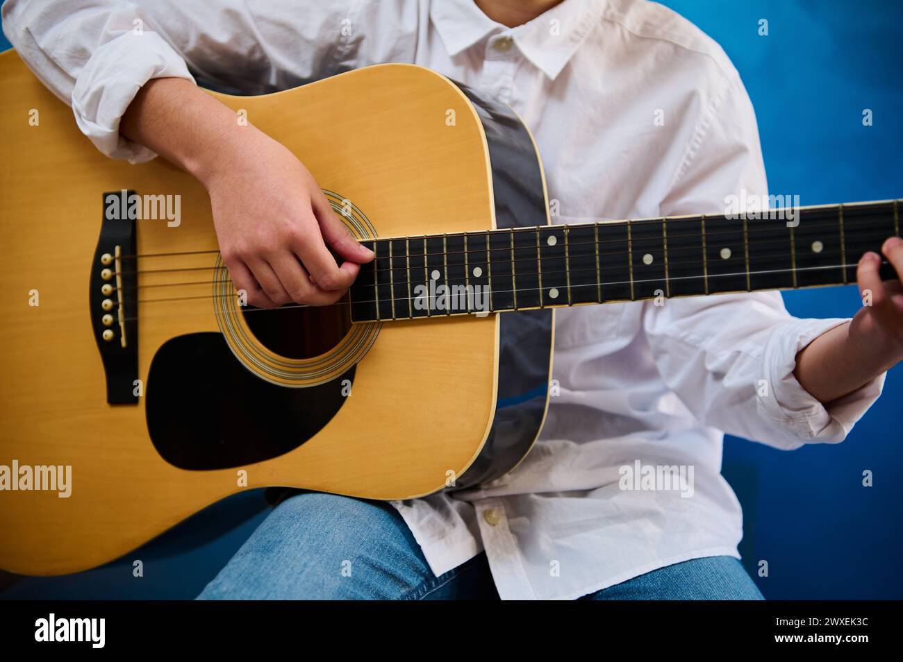 Child's hand plucking the strings while playing the guitar. Cropped ...
