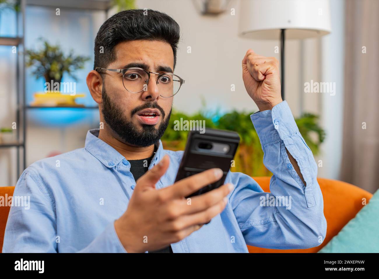 Shocked sad Indian young man using smartphone reading negative message ...