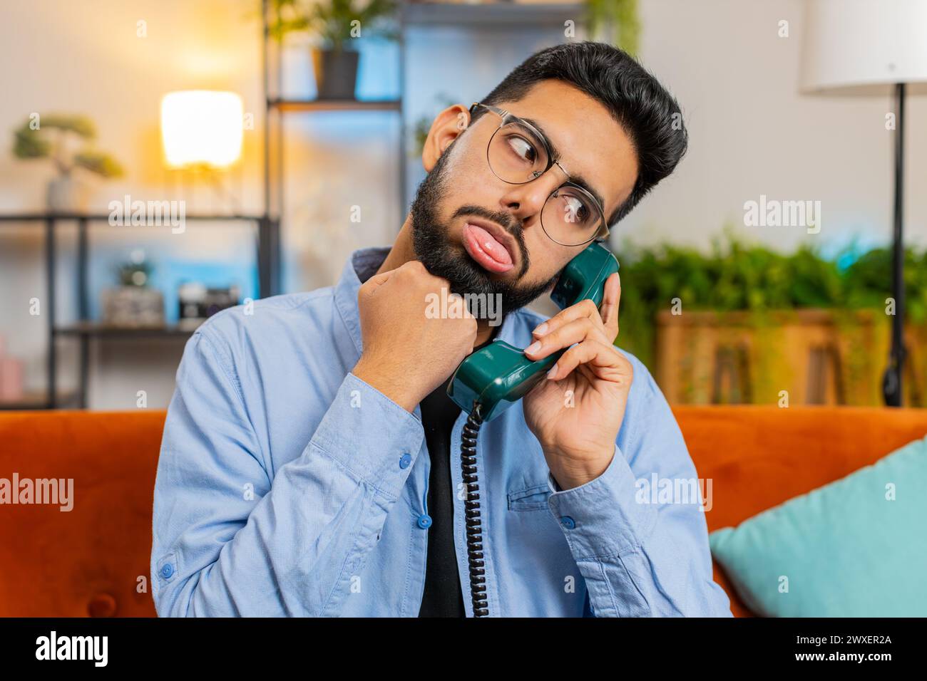 Irritated young Indian man talking on vintage retro wired telephone at ...